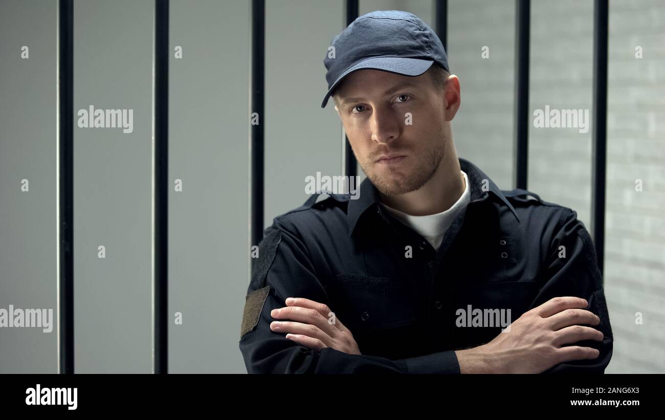 Confident prison security guard looking to camera standing near cell ...