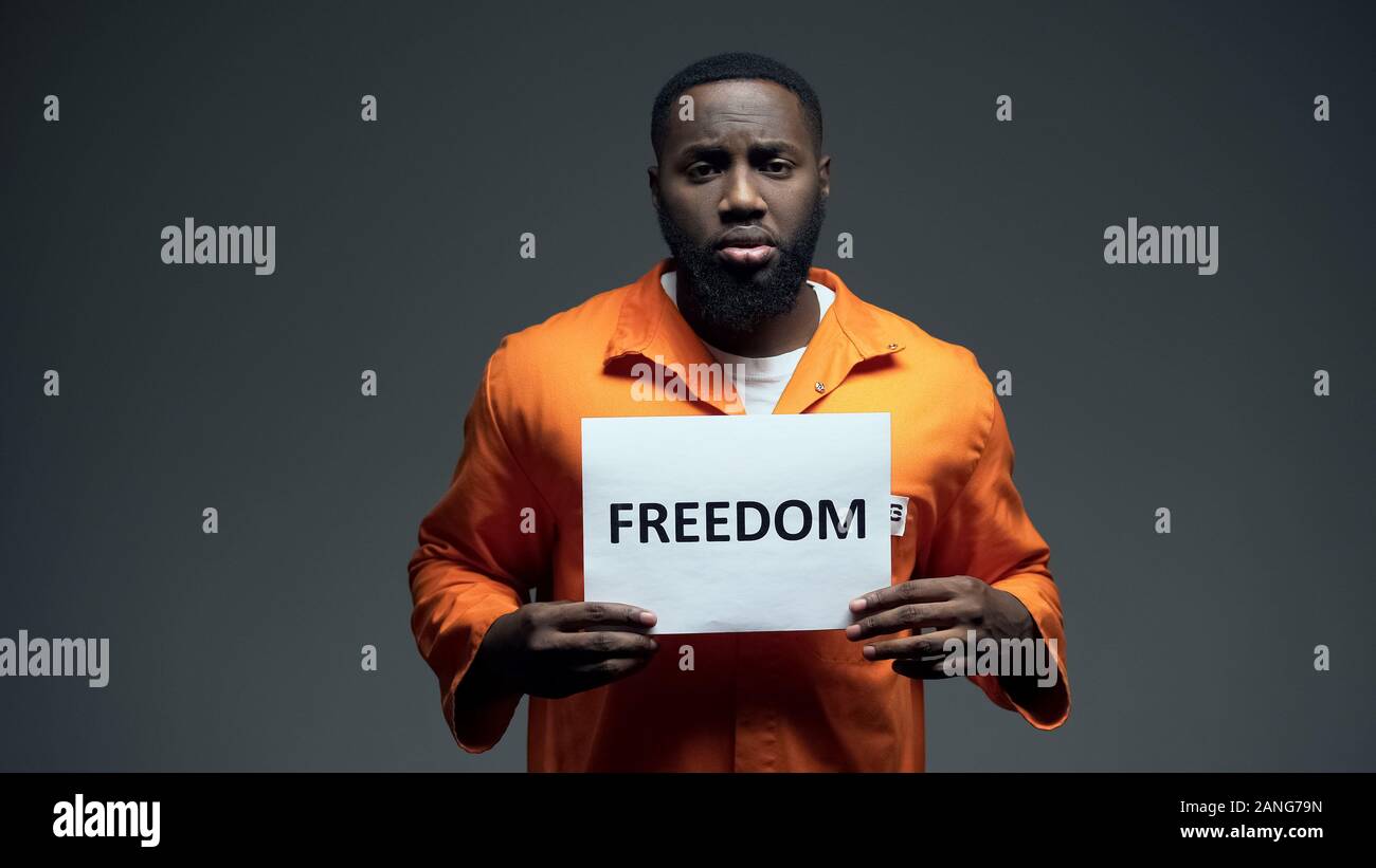 Black imprisoned male holding freedom sign in cell, asking for help ...