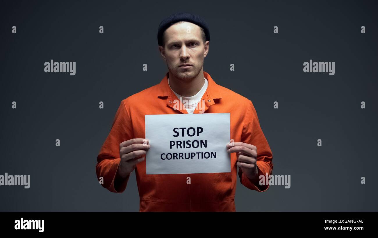 Caucasian imprisoned male holding stop prison corruption sign, faulty ...
