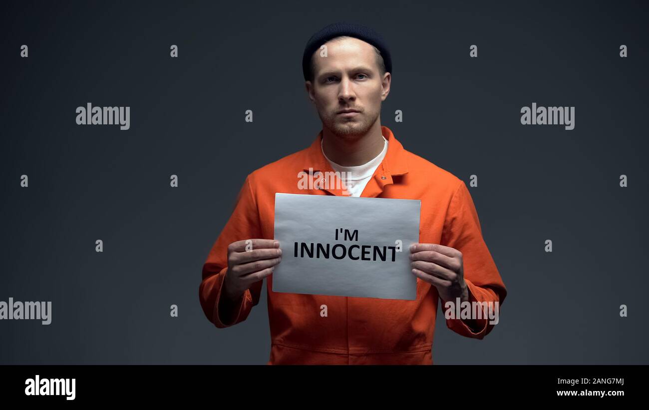 European imprisoned male holding I am innocent sign in cell, asking for ...
