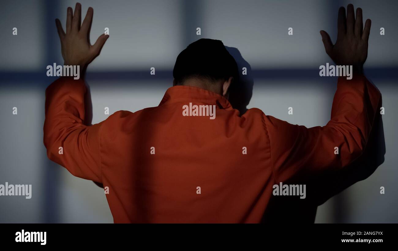 Caucasian prisoner standing near wall, security checkup in jail ...