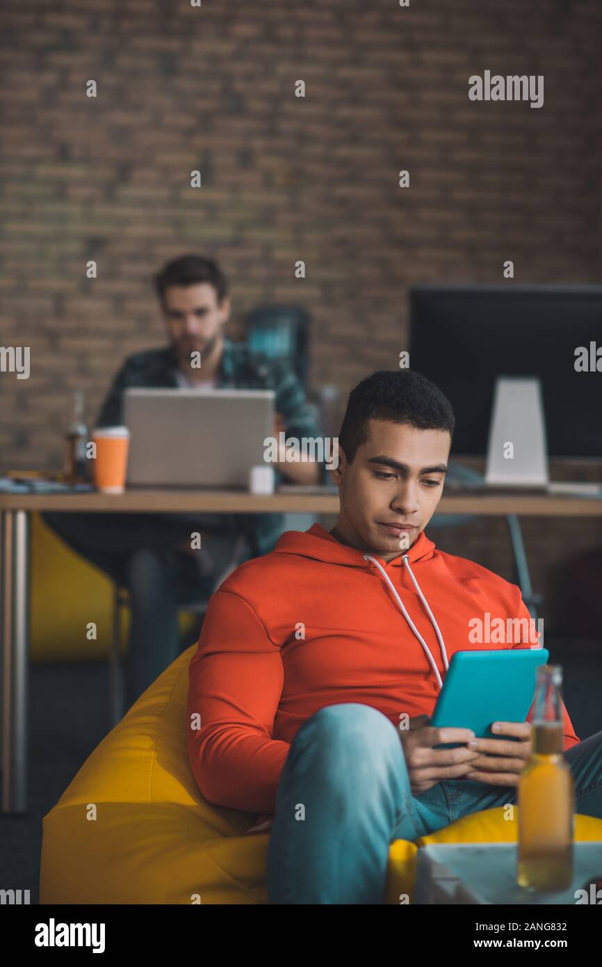 Serious young man looking at his tablet screen Stock Photo - Alamy