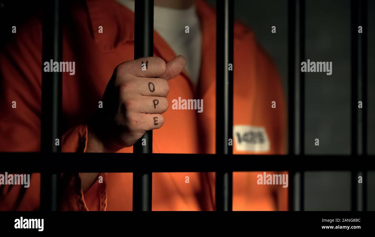 Hope word on imprisoned man fingers, holding jail bars, dream about ...