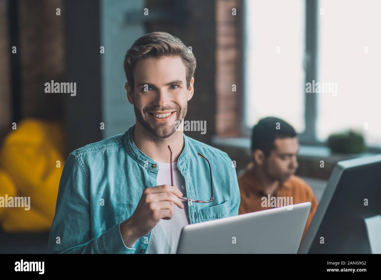 Delighted good looking man standing with his glasses Stock Photo - Alamy