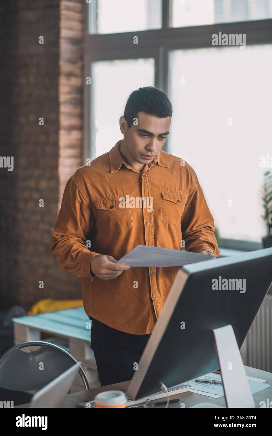 Good looking intelligent man standing near his desk Stock Photo - Alamy