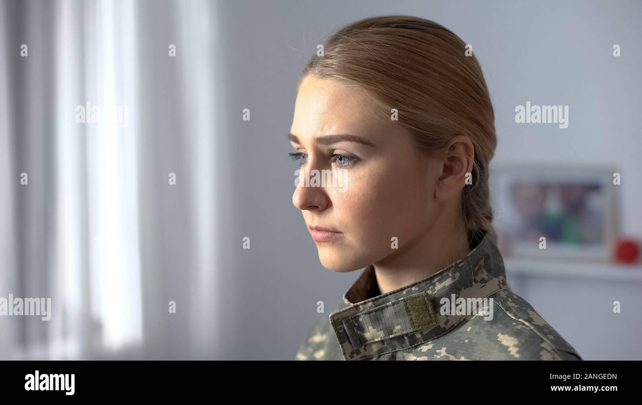 Upset female soldier in military uniform sadly looking in rehab center ...