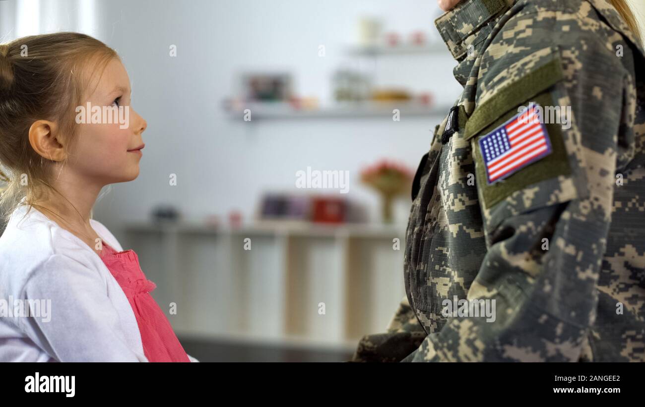 Cute daughter looking with love at mother in military form, happy ...