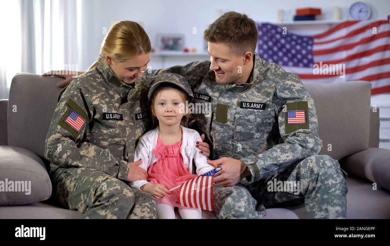 Smiling military parents looking at cute daughter with american flag ...