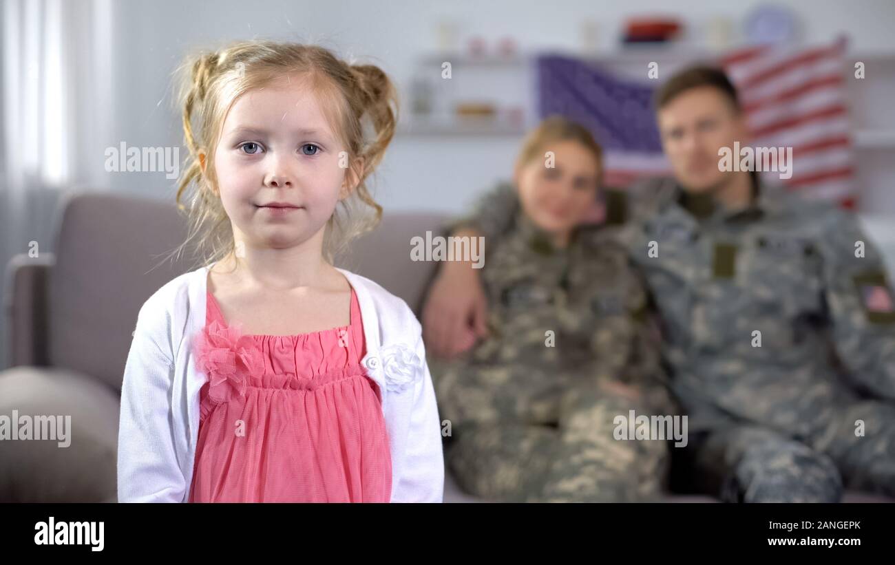 US military couple admiring little cute daughter looking at camera ...