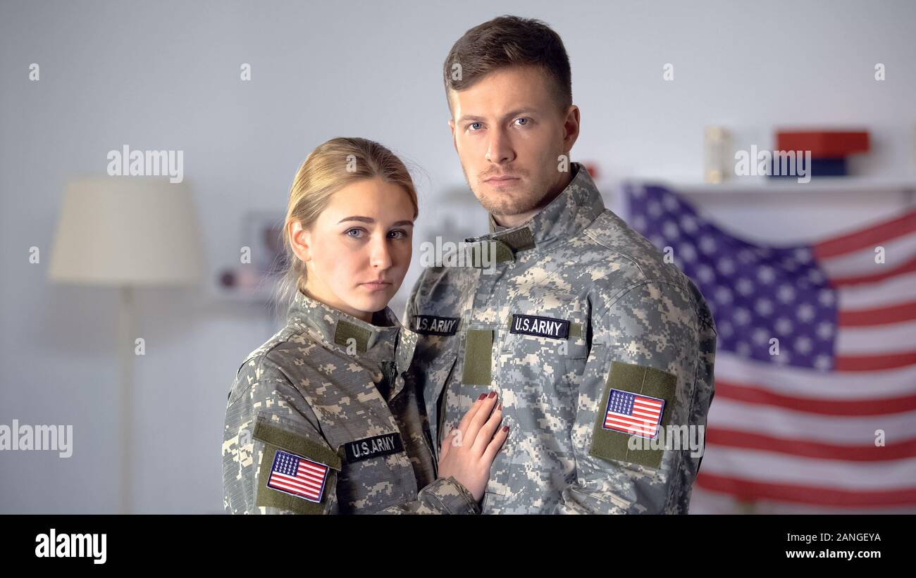Serious male and female US soldiers hugging and looking at camera, war ...