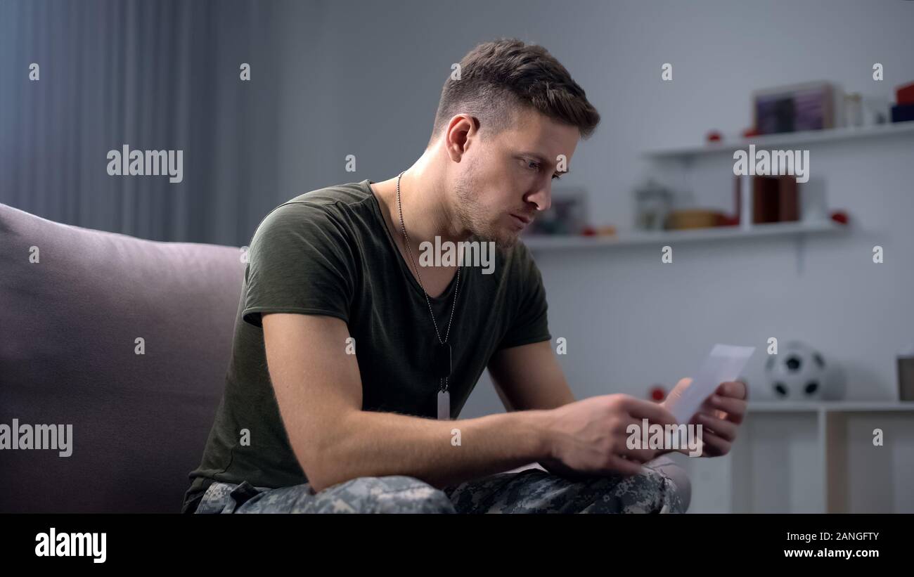 Disappointed soldier looking at family photo, relationship problem ...