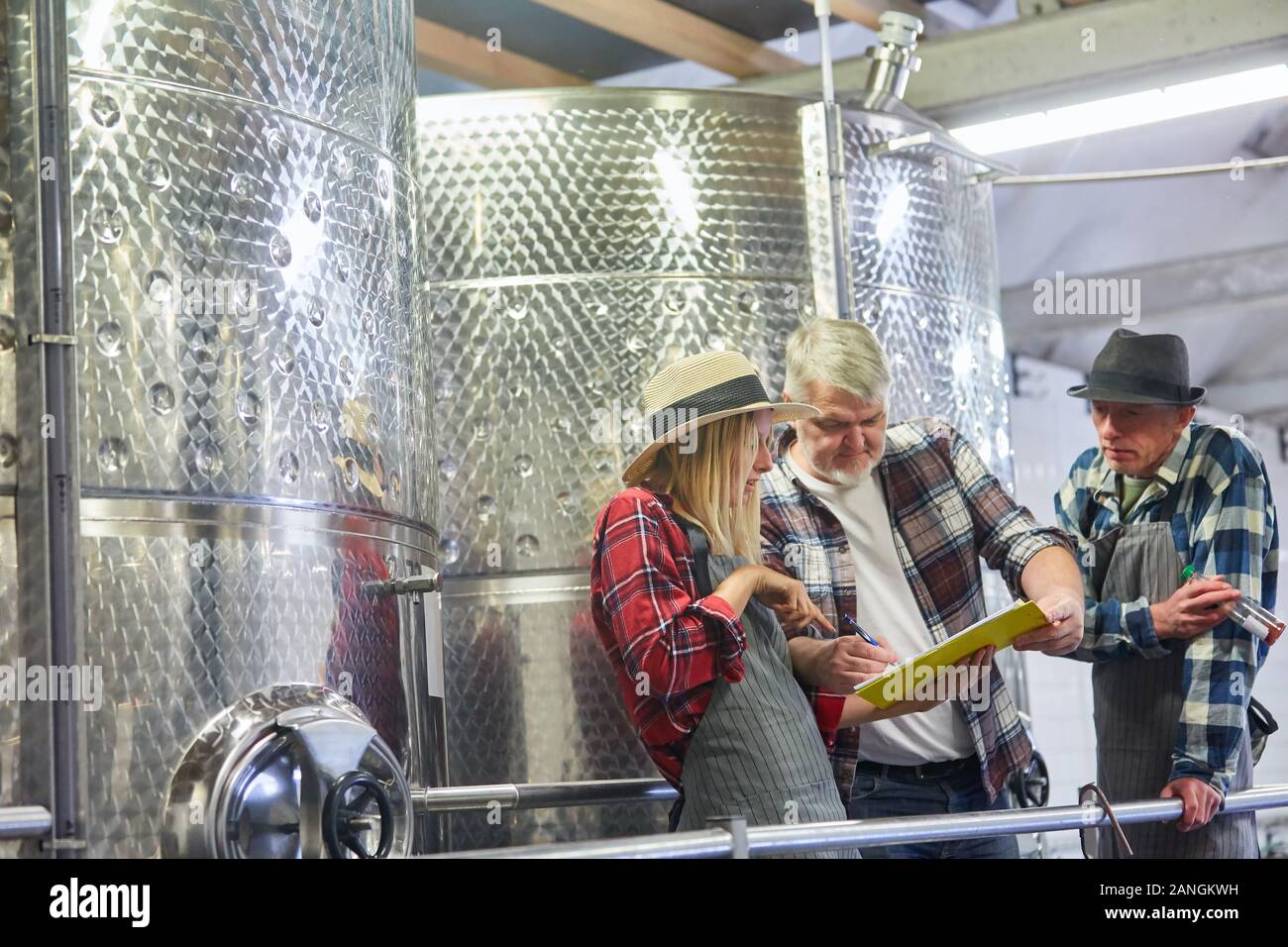 Group of workers with checklist in brewery or winery in front of a ...
