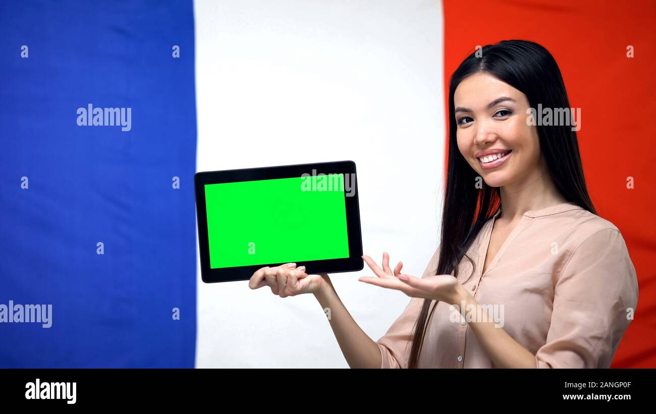 Girl holding tablet with green screen, France flag on background ...