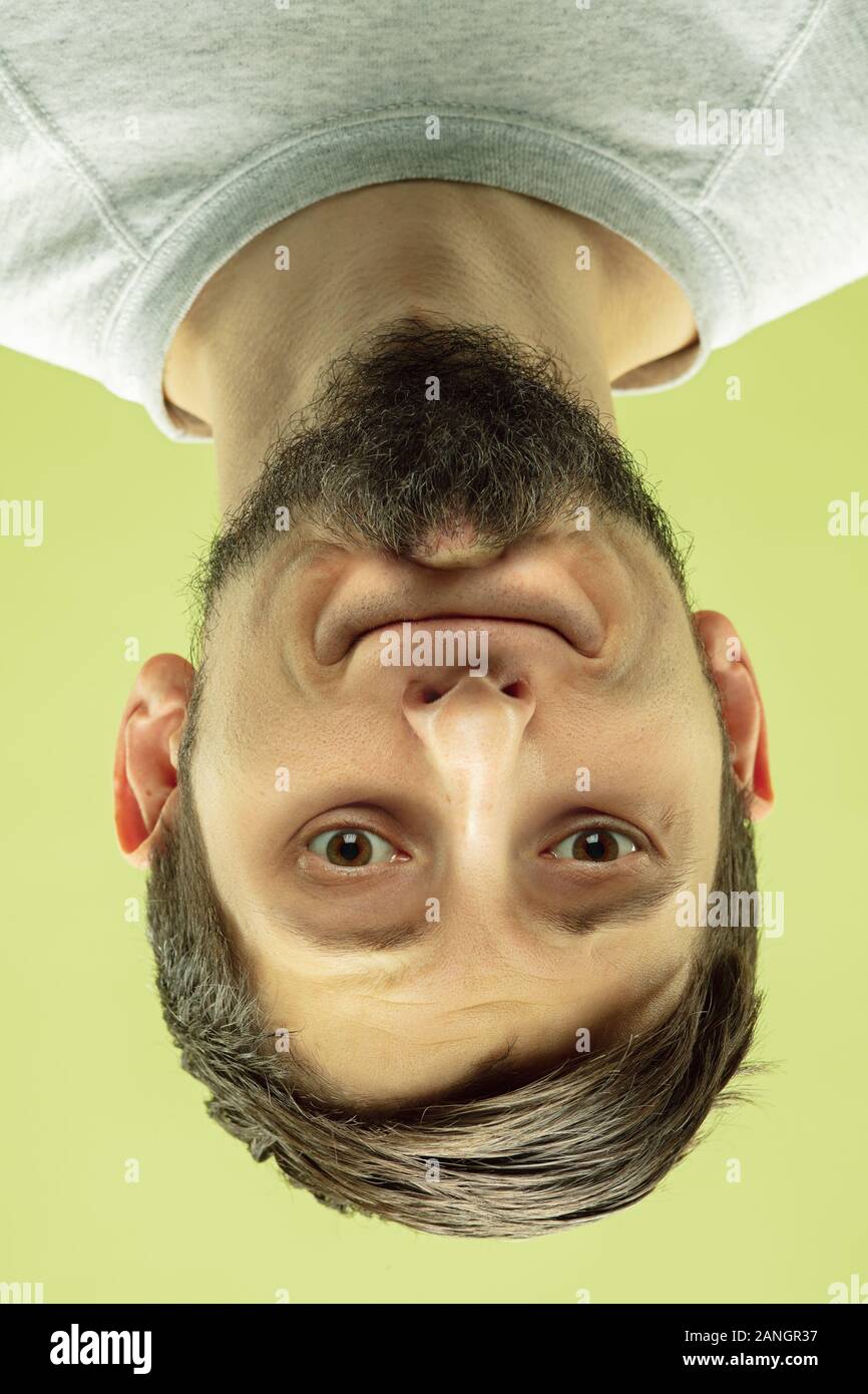 Smiling and happy. Inverted portrait of caucasian young man on yellow ...