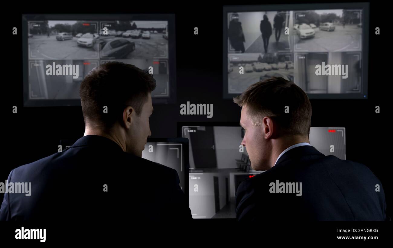 Two detectives checking surveillance camera records after crime ...