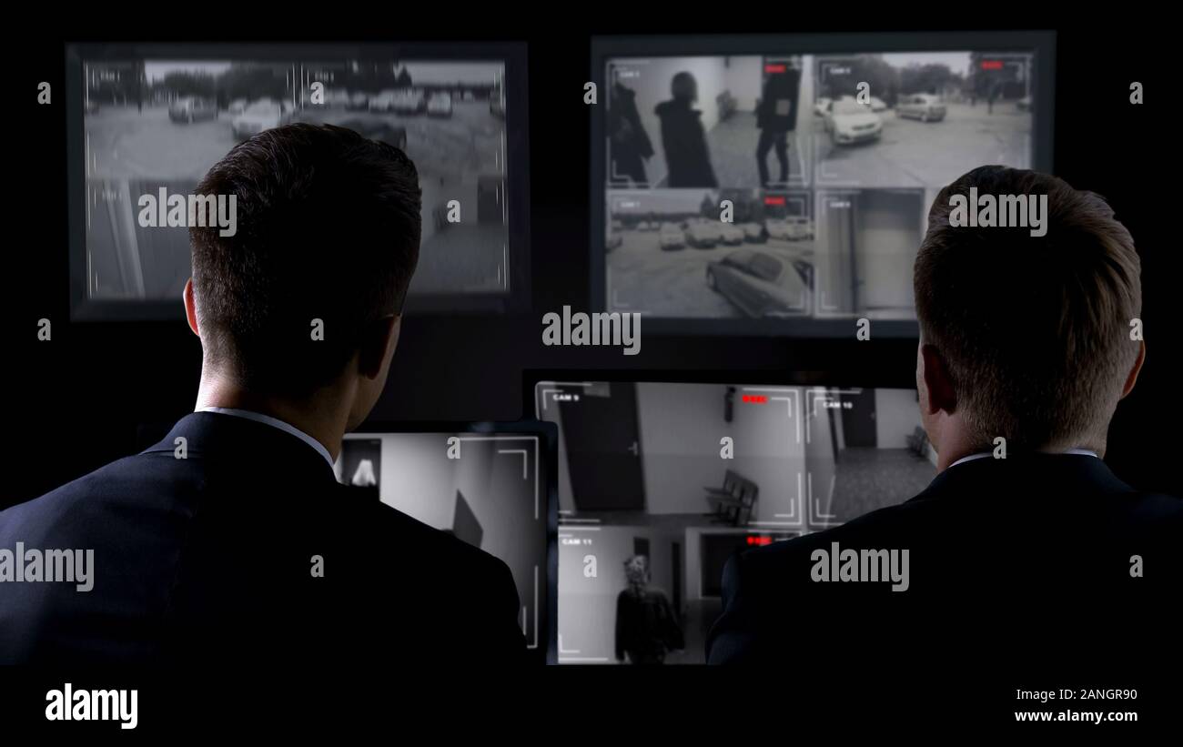 Security guards watching surveillance cameras, guarding important ...