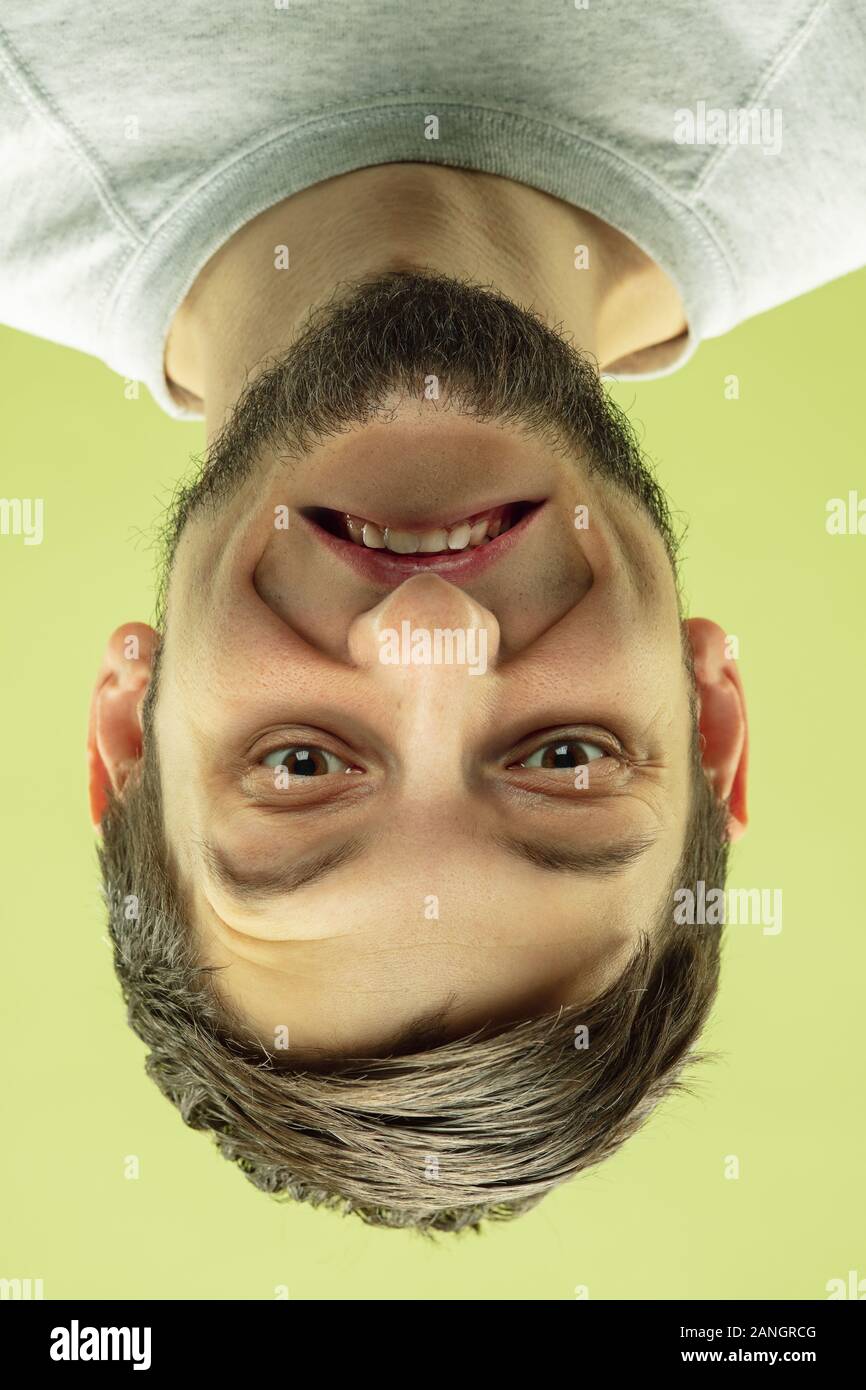 Smiling and happy. Inverted portrait of caucasian young man on yellow ...