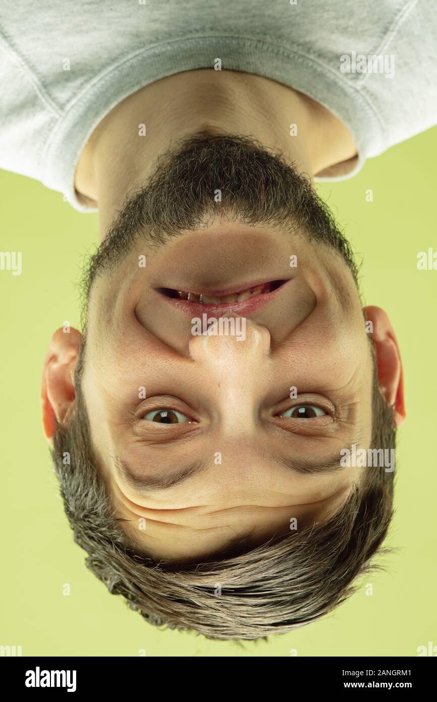 Smiling and happy. Inverted portrait of caucasian young man on yellow ...