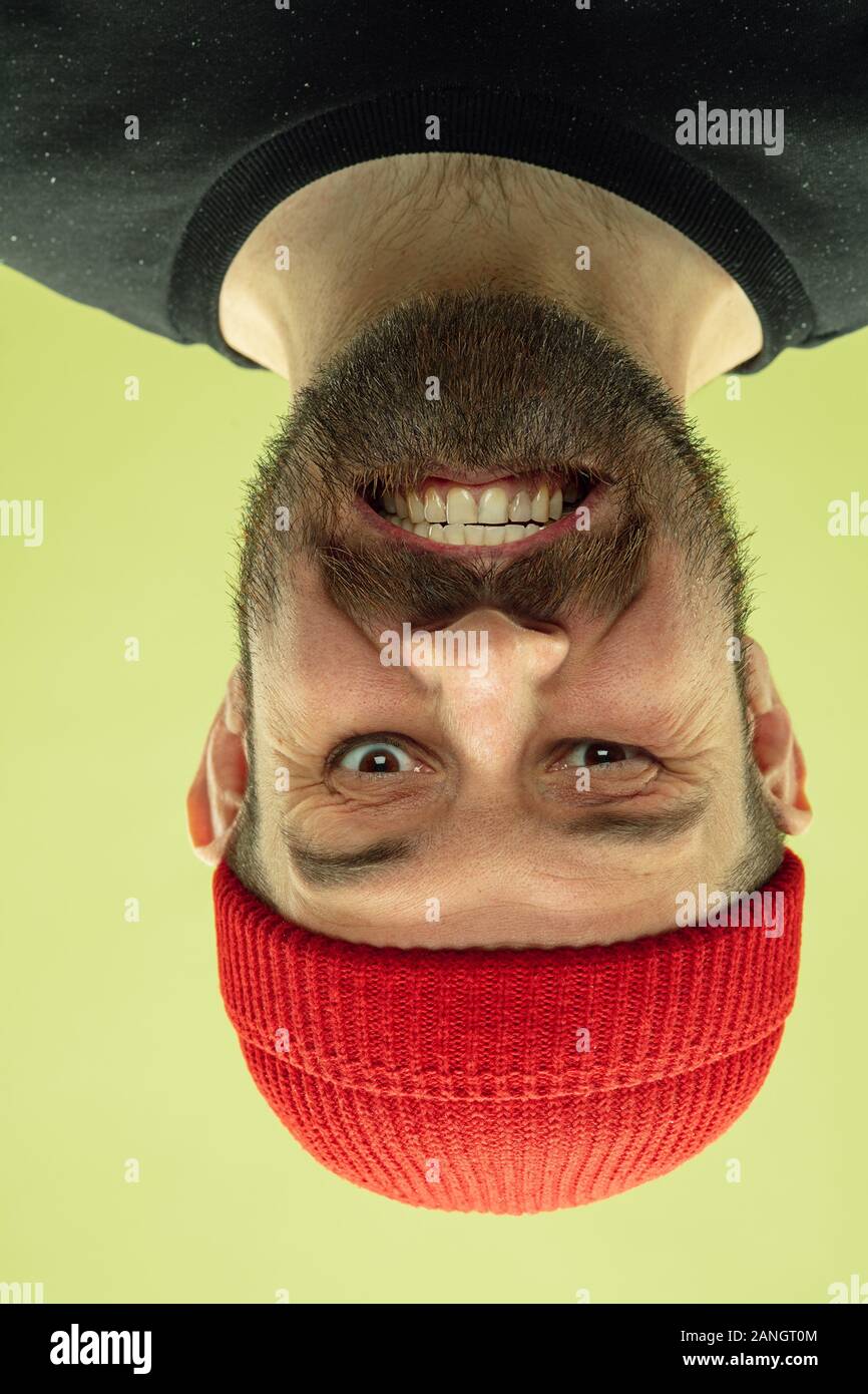 Crazy, smiling. Inverted portrait of caucasian young man on yellow ...
