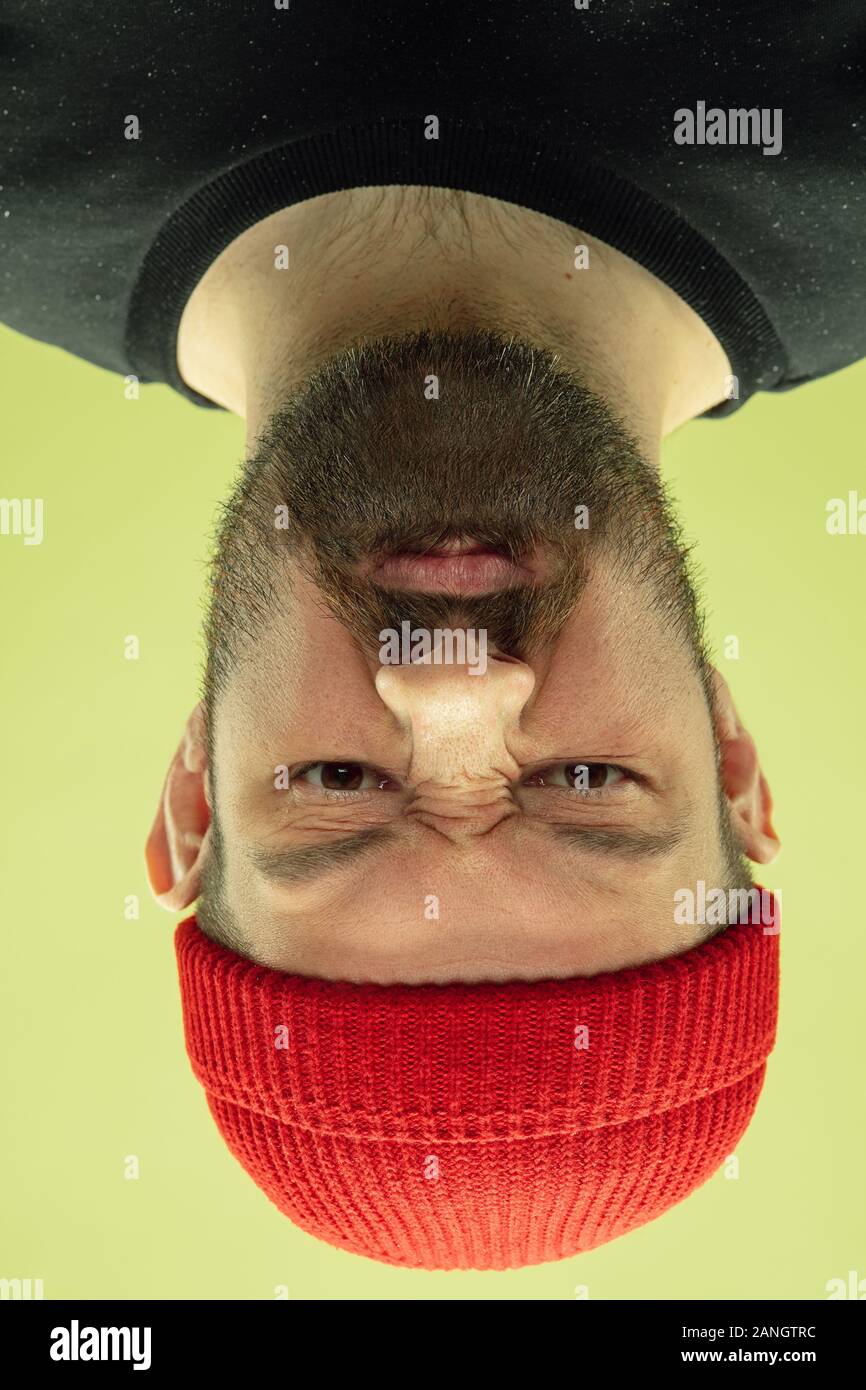 Angry, sad, scary. Inverted portrait of caucasian young man on yellow ...