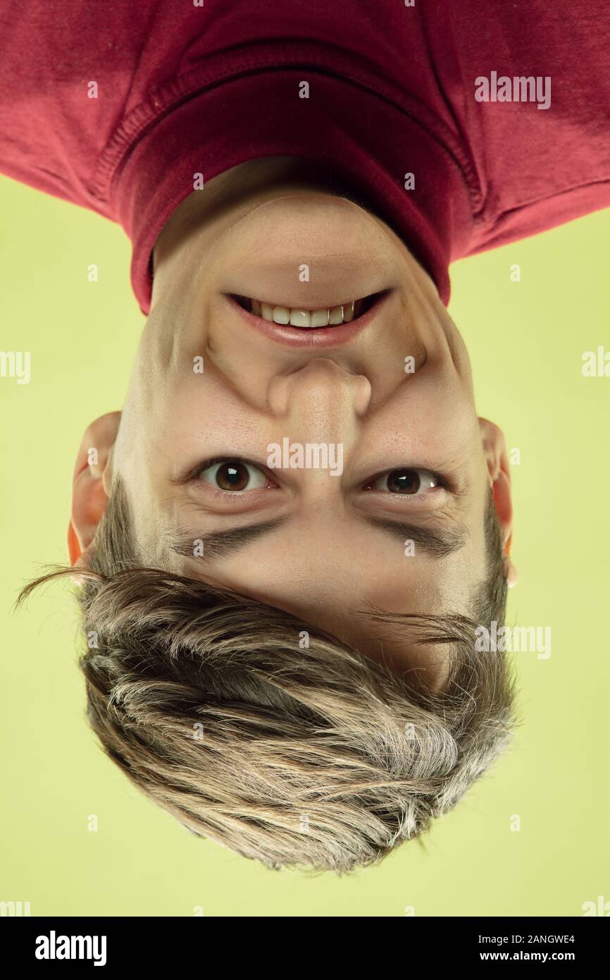 Smiling cute, looks happy. Inverted portrait of caucasian young man on ...