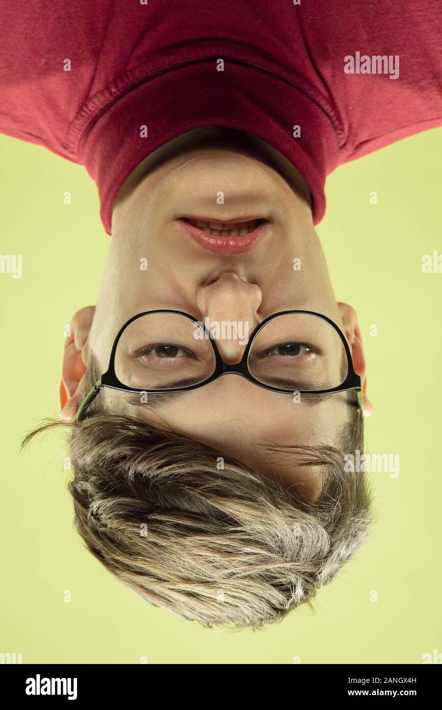 Looks angry, scary. Inverted portrait of caucasian young man on yellow ...