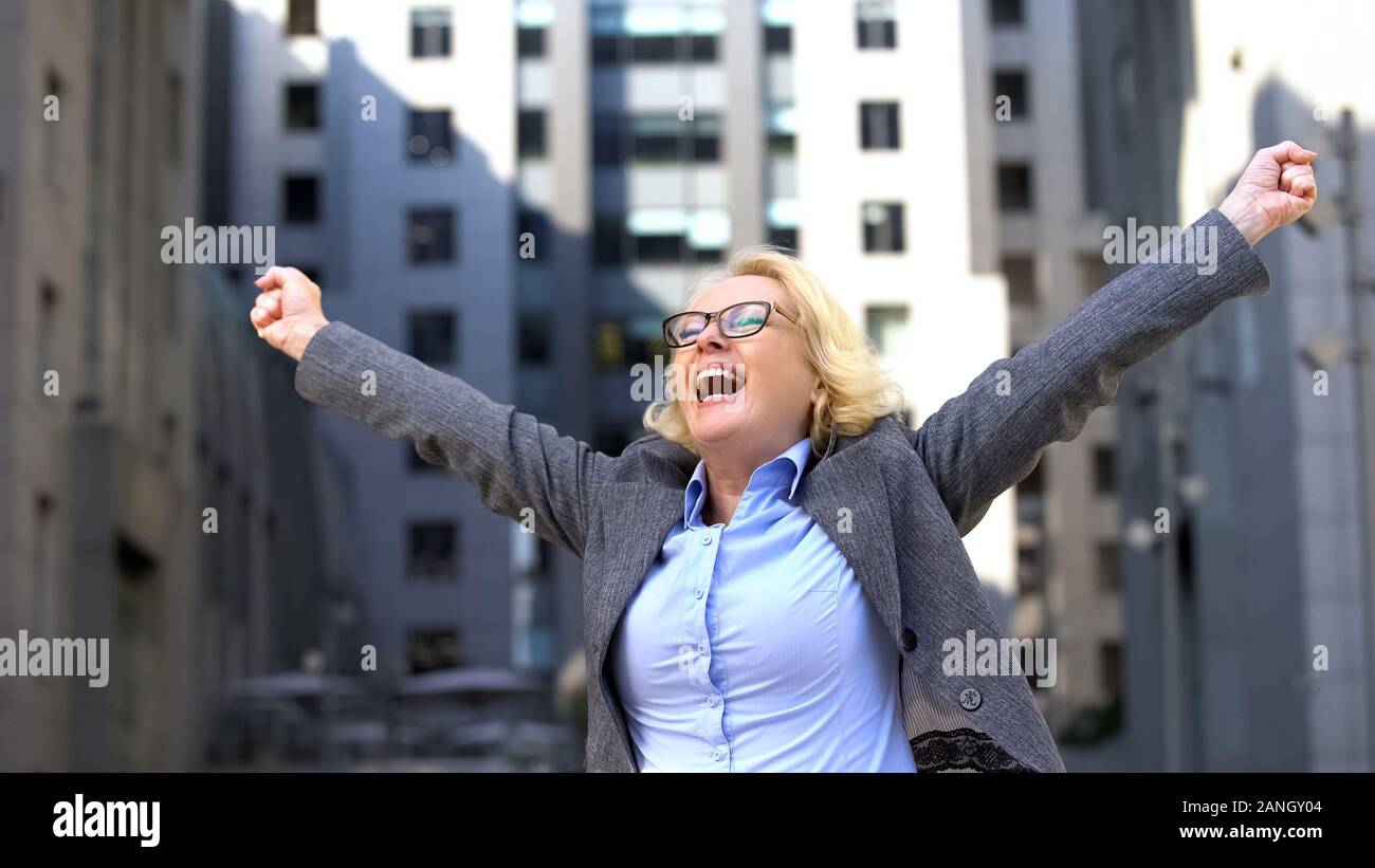 Joyful business lady showing yes gesture raising hands up, goal ...