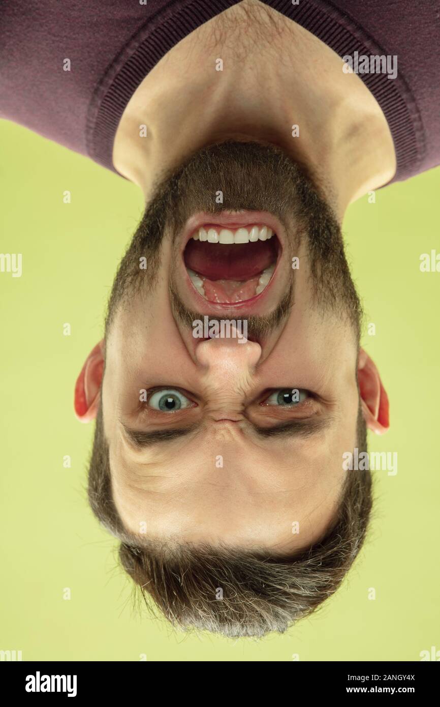 Angry screaming, scary. Inverted portrait of caucasian young man on ...