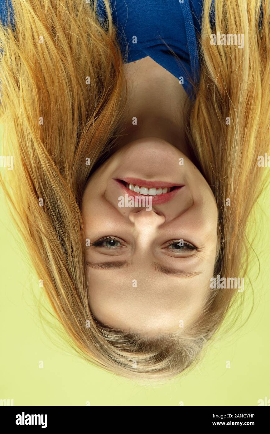 Smiling, looks happy. Inverted portrait of caucasian young woman on ...