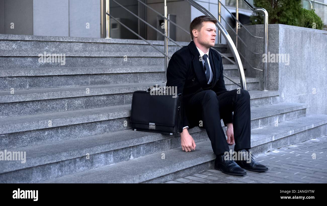 Depressed young man sitting office stairs, job interview failure ...