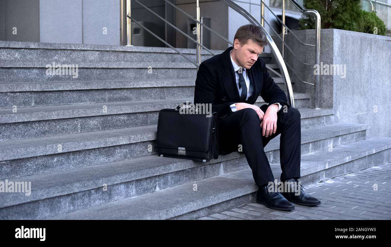 Sad man in business suit sitting office building stairs, dismissal ...