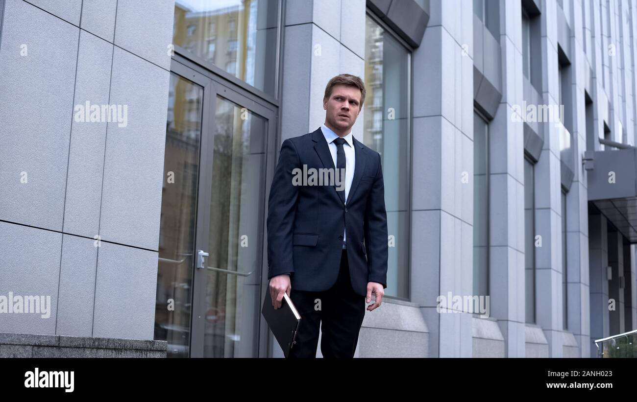 Worried office manager standing outdoors holding documents, unhappy ...