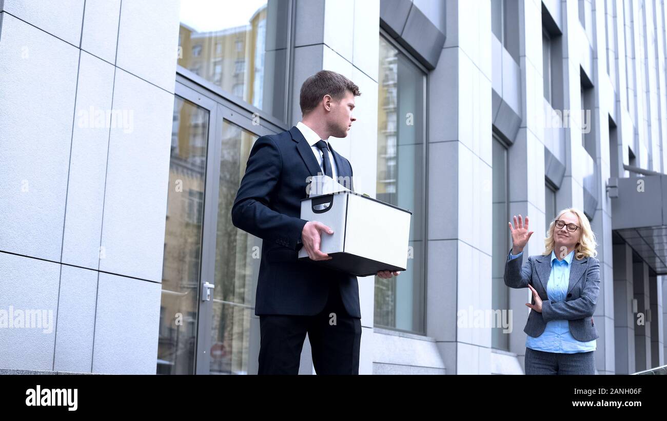 Sad male manager with stuff box looking gloating female boss, company ...