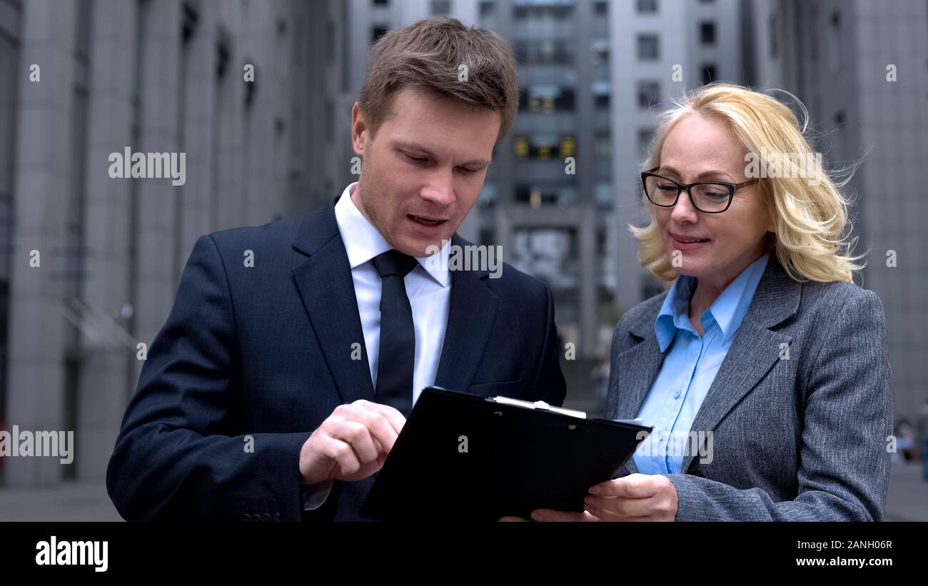 Business partners analyzing sales report document together, project ...