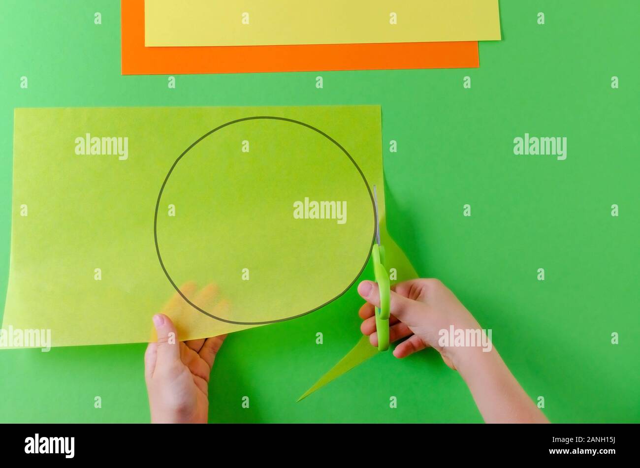 child's hands cut circle on transparent paper with scissors, top view ...