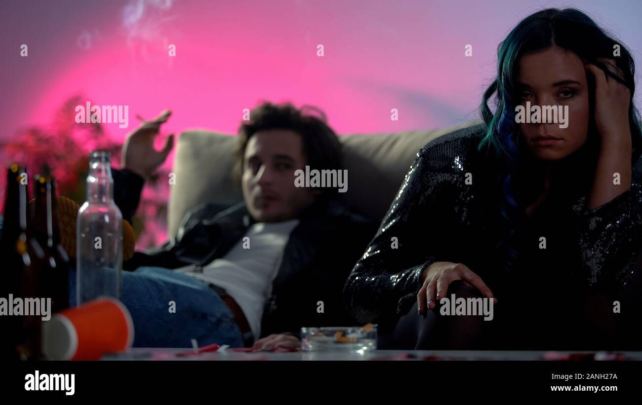 Couple of intoxicated young people sitting relaxed in messy room, night ...