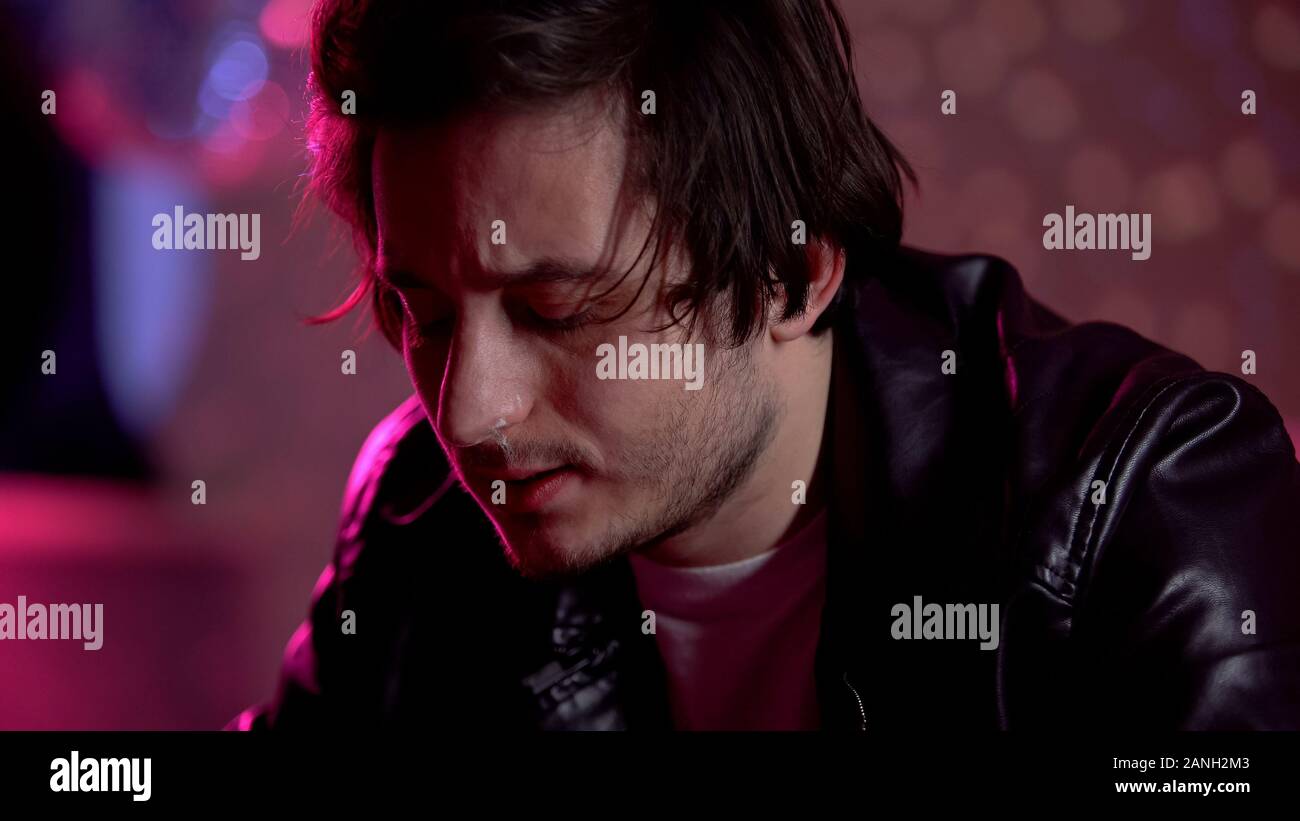 Pensive man with coke powder on nose sitting in night club, rave party ...