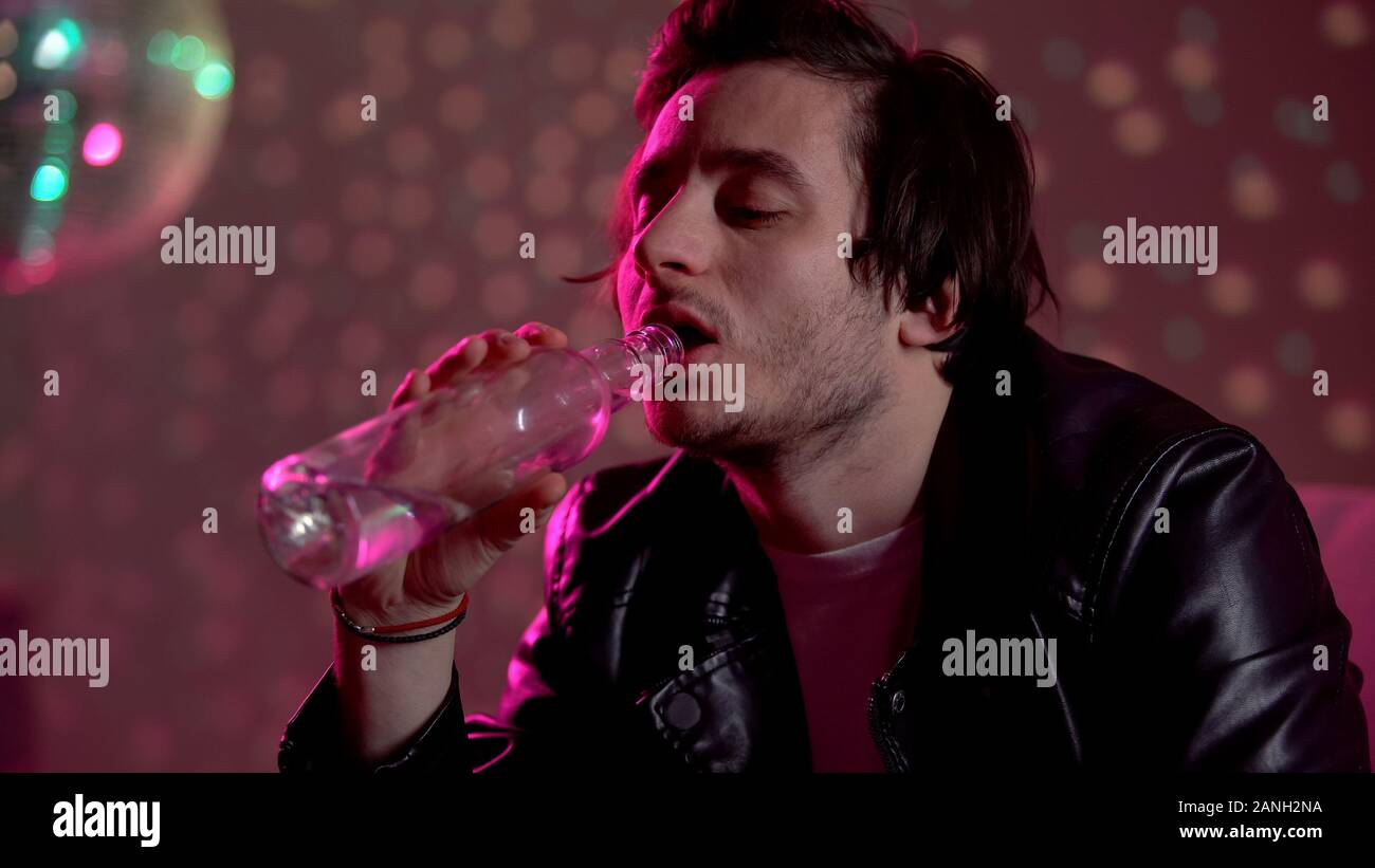 Man drinking vodka from bottle at party, suffering depression, alcohol ...