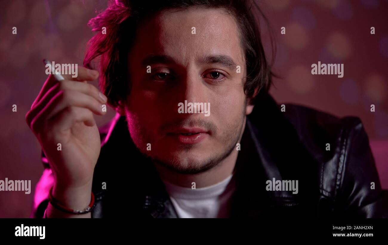 Distressed guy with cigarette staring at camera, eyes full of tears ...