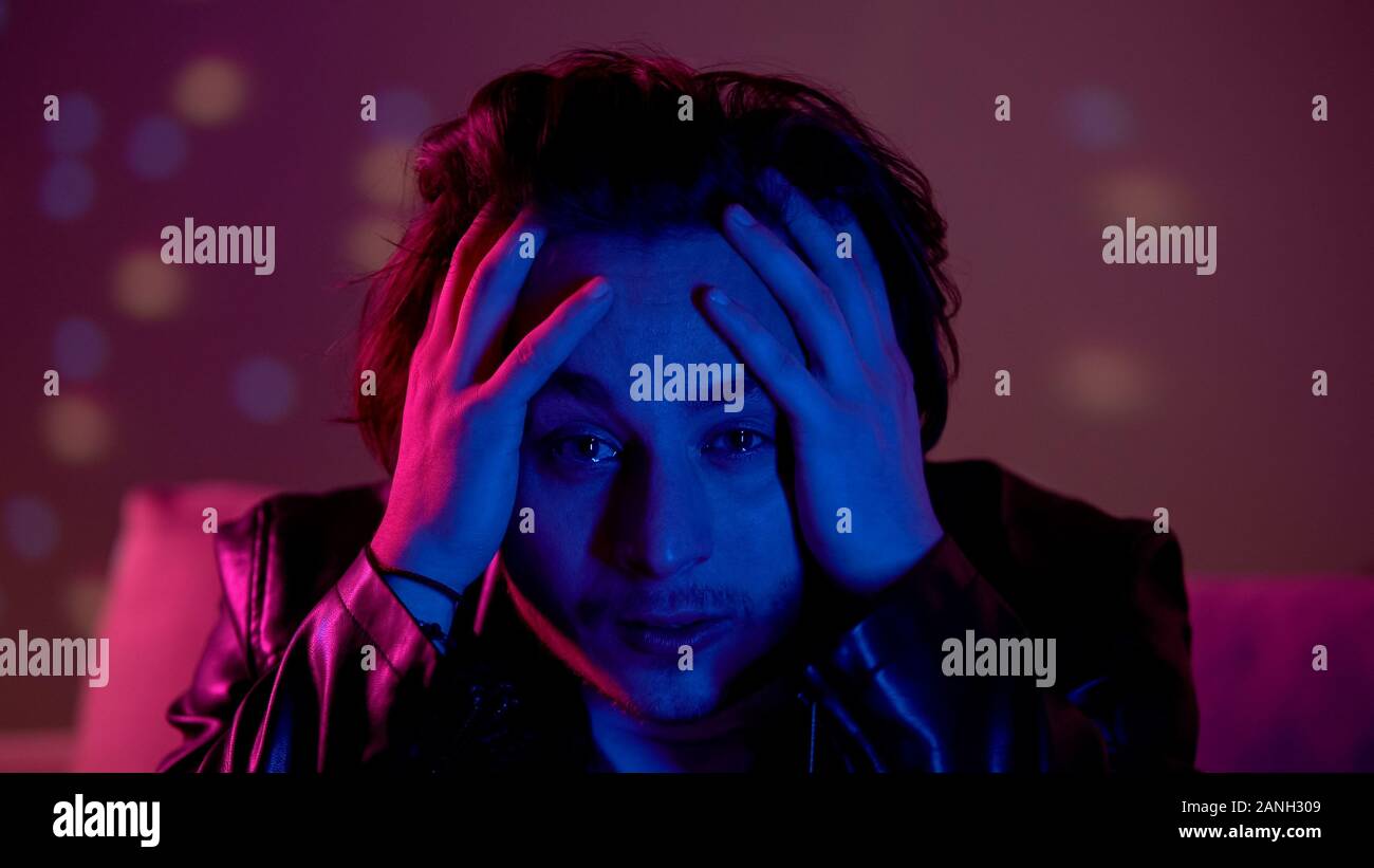 Frustrated male crying and holding head in night club, anxiety and ...