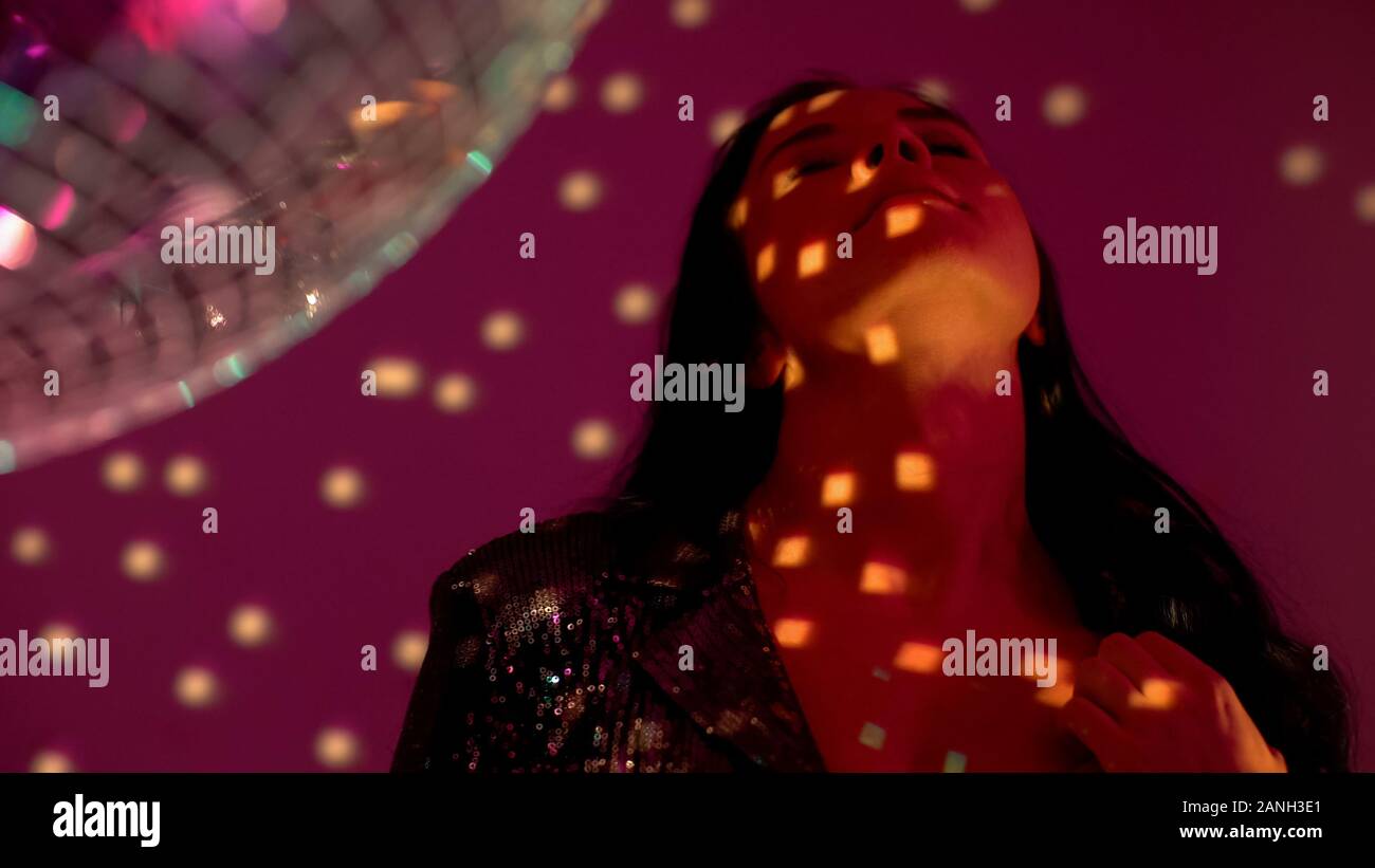 Pretty woman dancing by disco ball at party in night club, escape from ...