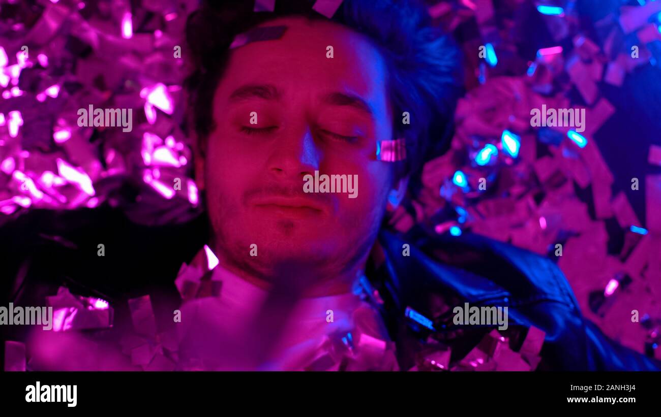 Male sleeping on floor of night club among confetti, partying all night ...
