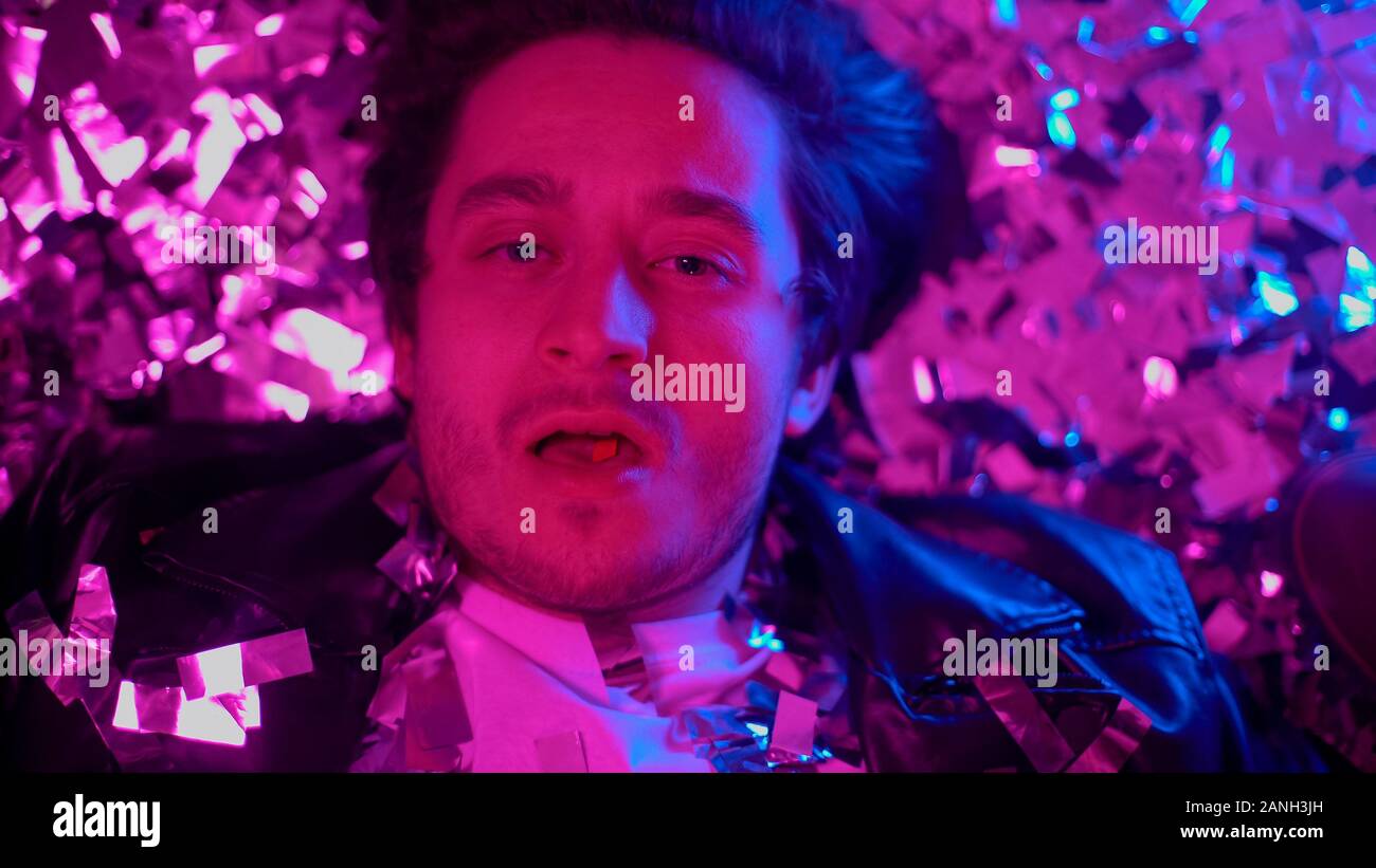 Guy taking ecstasy blotter to have fun at party, lying on floor, drug ...