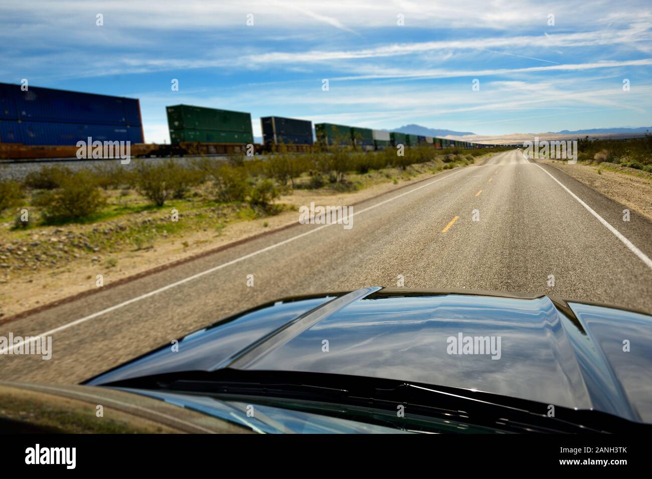 Car driving on deserted, straight freeway portion, parallel to railroad ...
