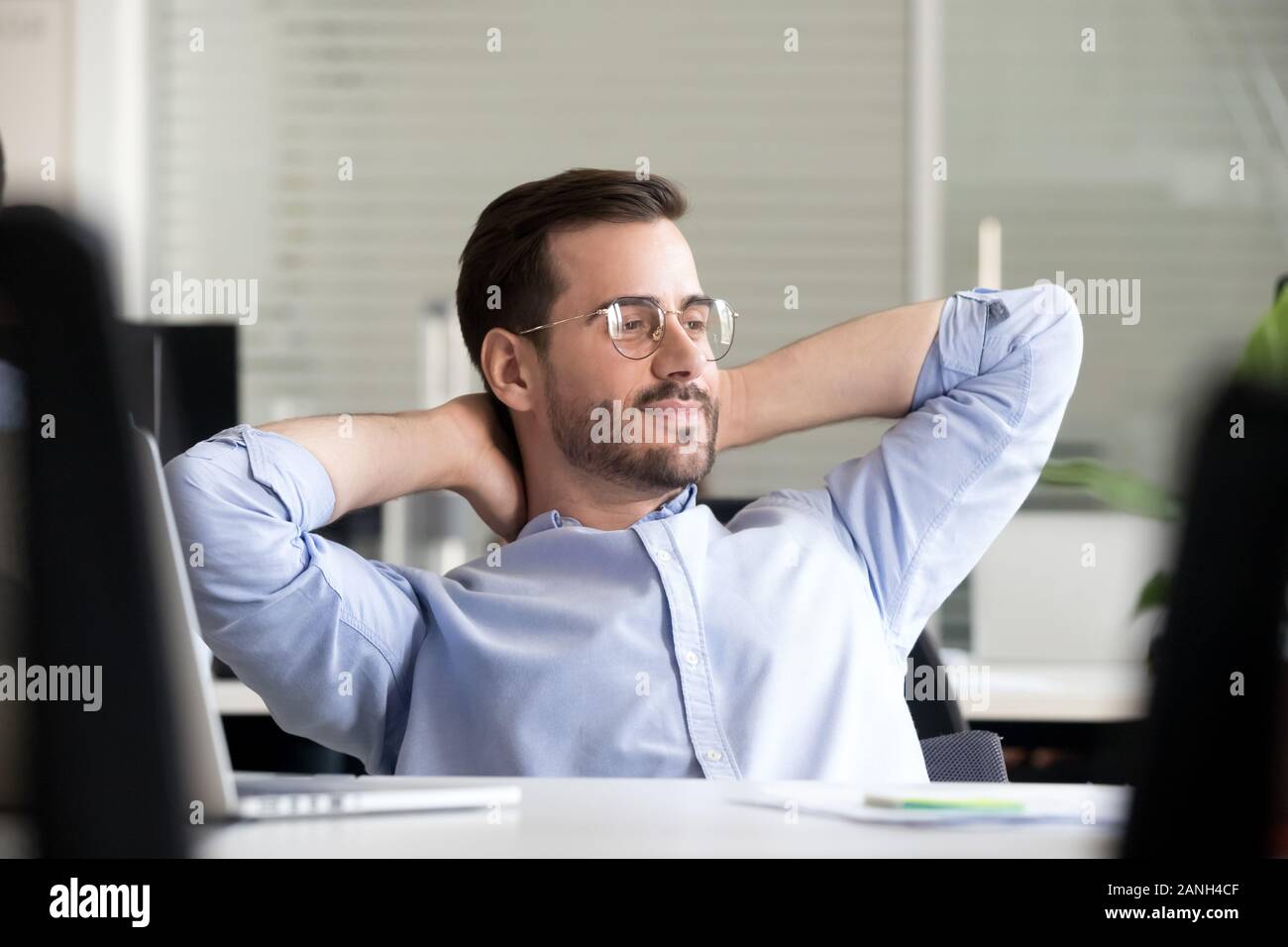 Dreamy male employee relax in chair hands over head looking distance ...