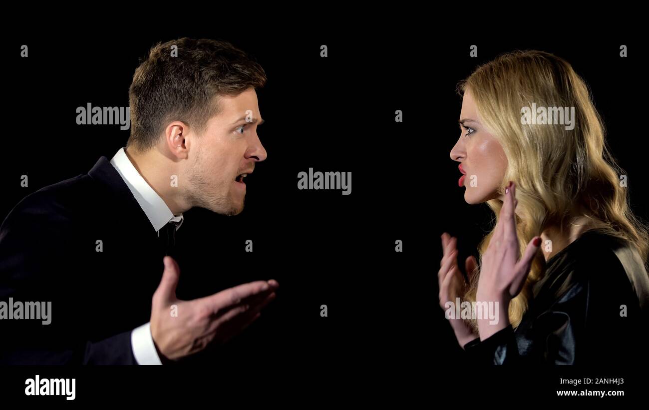 Young couple emotionally arguing against black background ...
