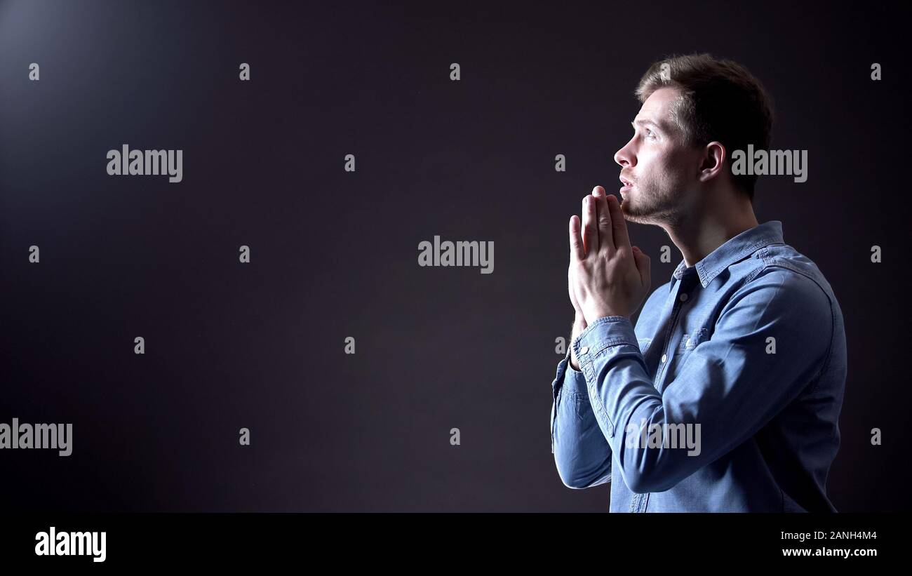 Young male praying, blessing God under light from heaven, Christianity ...