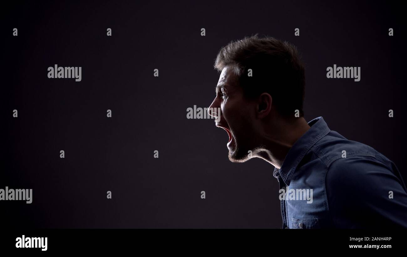 Frustrated man emotionally screaming isolated on black background, life ...