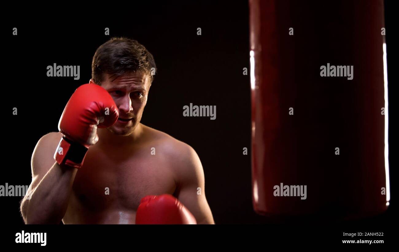 Sweaty sportsman training with boxing bag, fighting with insecurities ...
