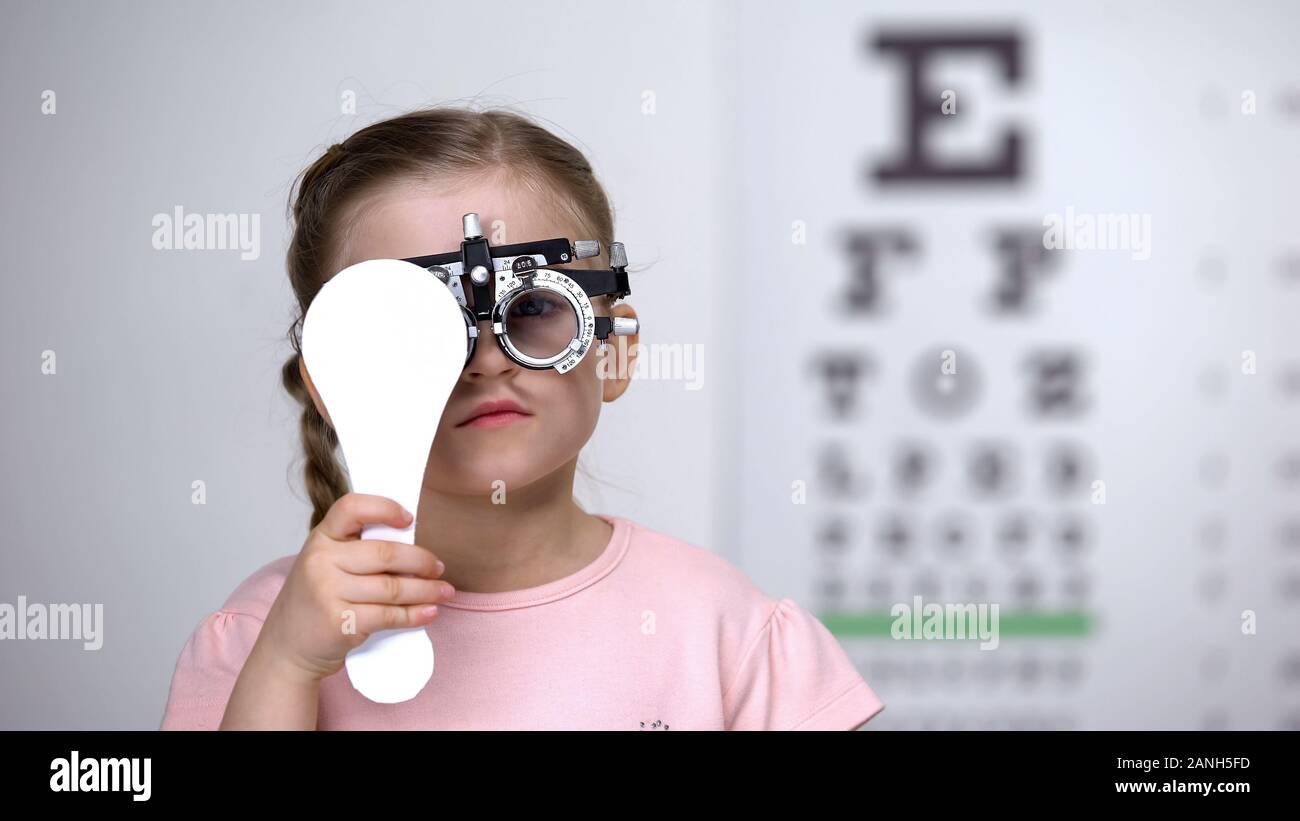 Child in special glasses with eye closed checking vision, astigmatism ...